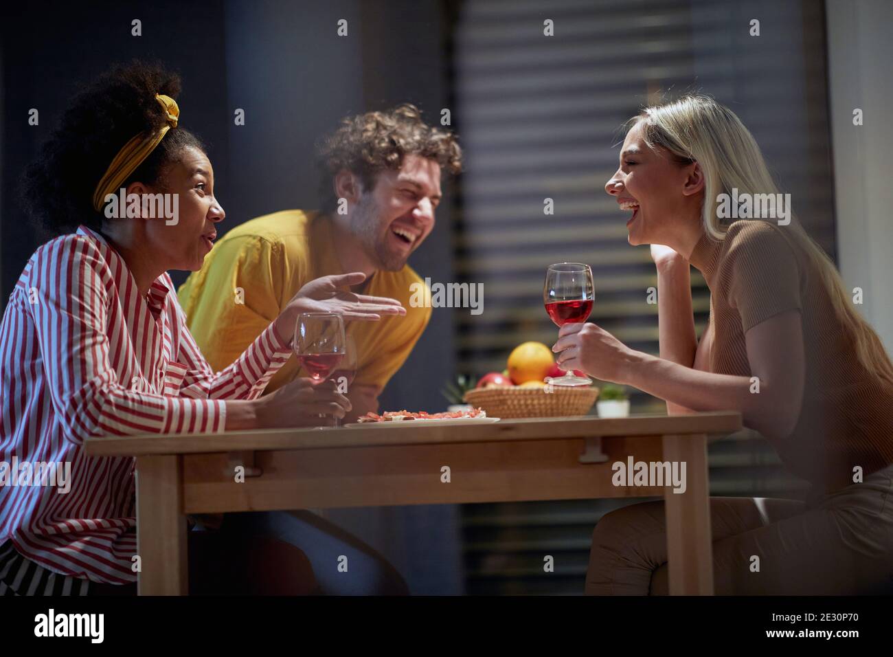 Group of three friends having home gathering together Stock Photo - Alamy