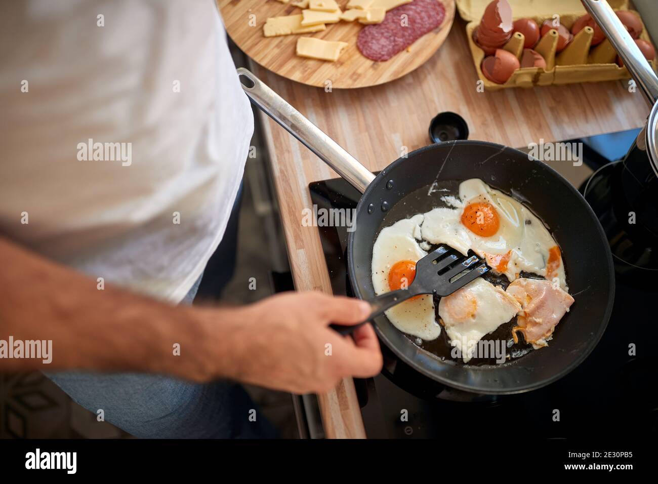 A young man frying the eggs on a beautiful morning in the kitchen Stock ...