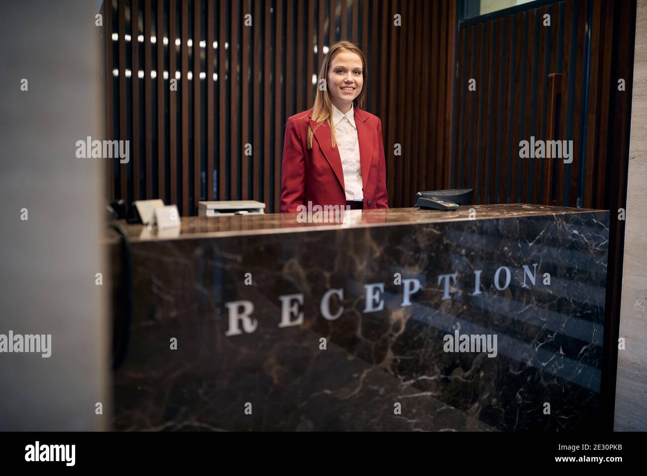Female receptionist waiting for the guests at the workplace in the ...