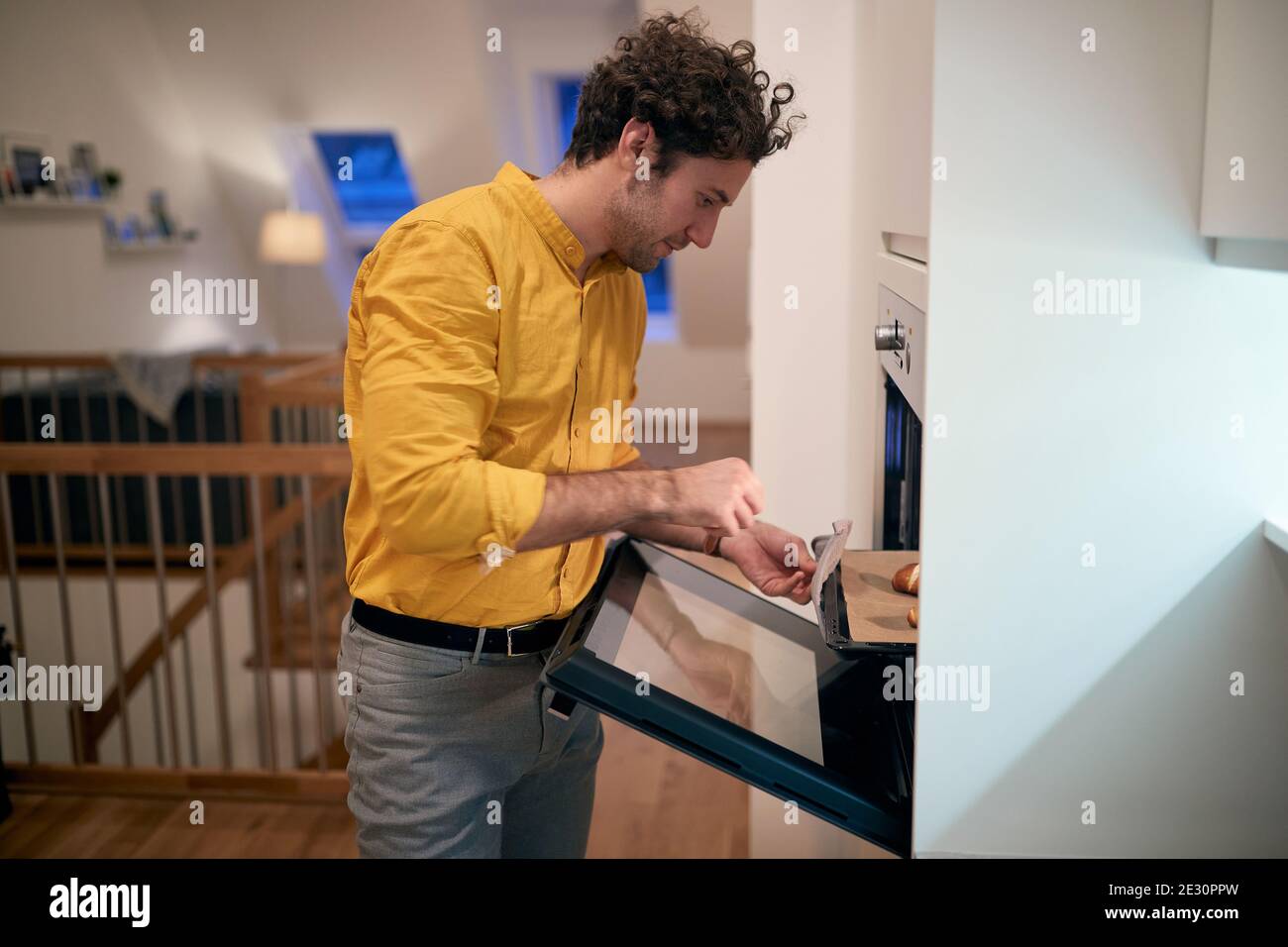 A young man baking pastry in a relaxed atmosphere at the kitchen. Food ...
