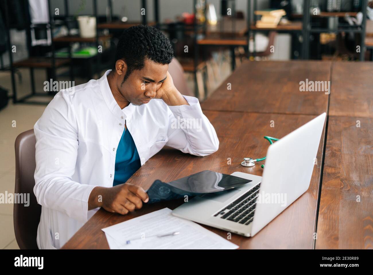Side view of ponder African American black male doctor in white coat ...