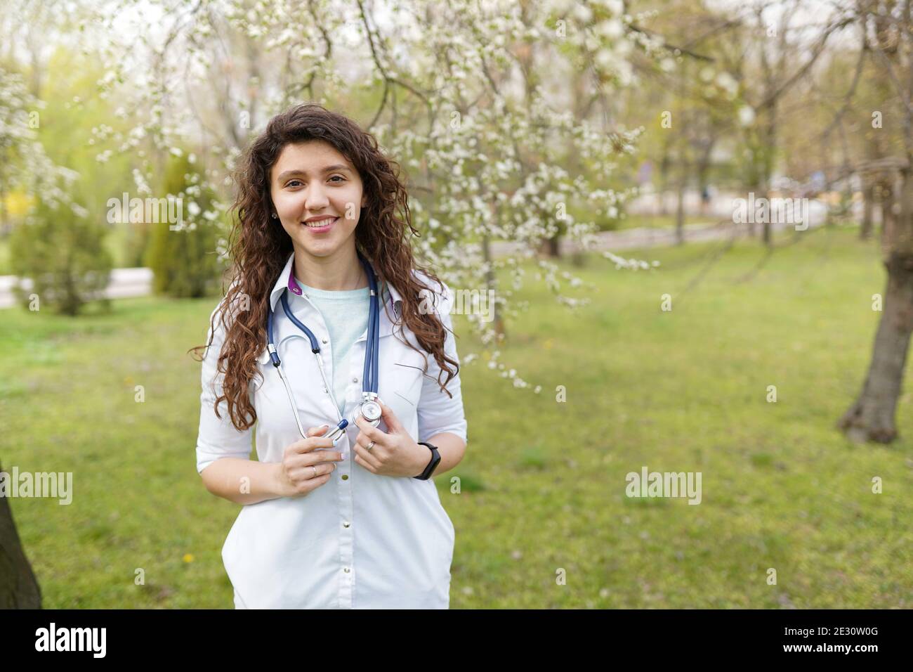 female doctor with stethoscope outdoors of a hospital in flower garden ...