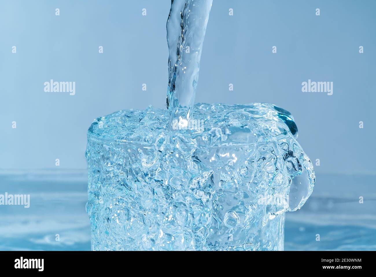 Pouring clean drinking water from blue plastic bottle into glass on ...