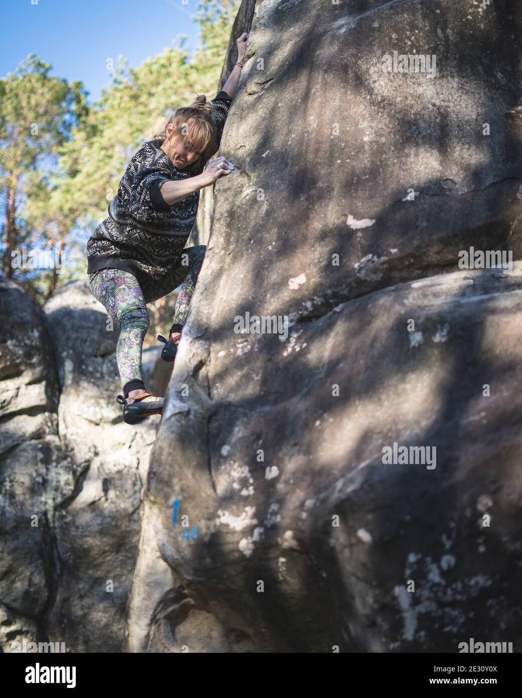 A female climber bouldering outdoors on the sandstone rocks of ...