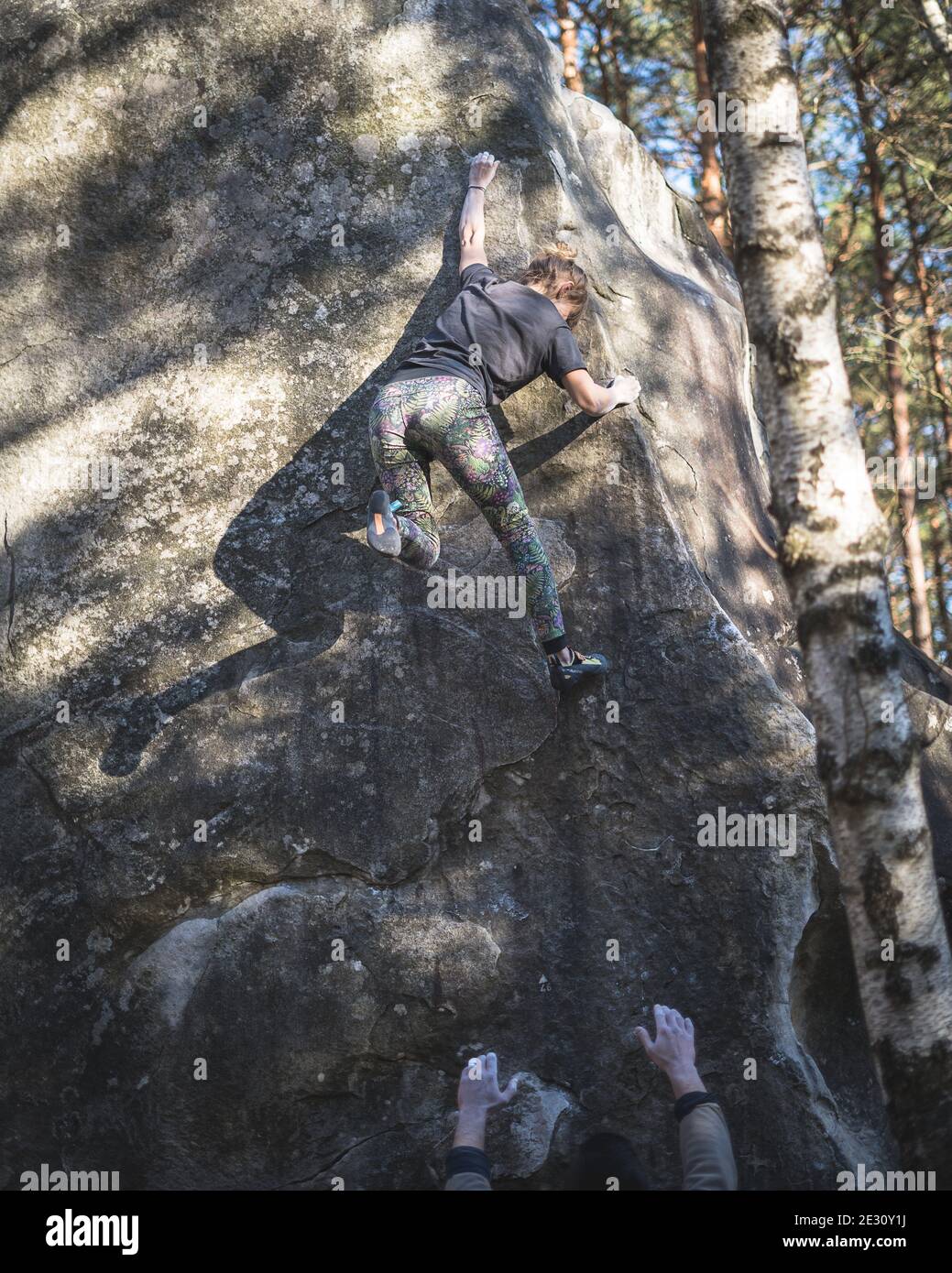 A female climber bouldering outdoors on the sandstone rocks of ...