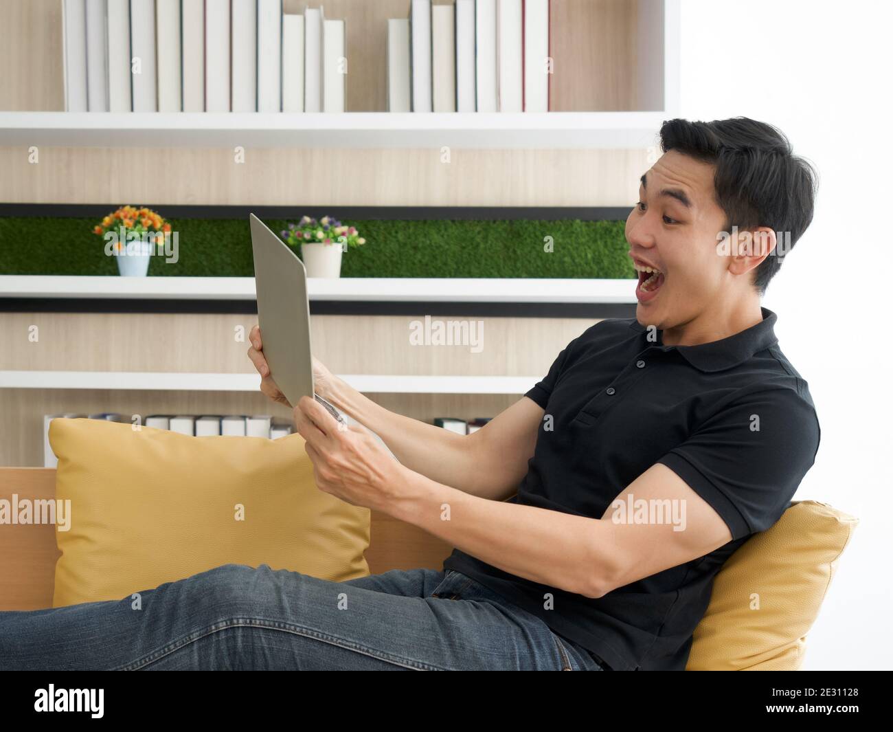 The young man wore comfortable clothes makes a happy expression while ...