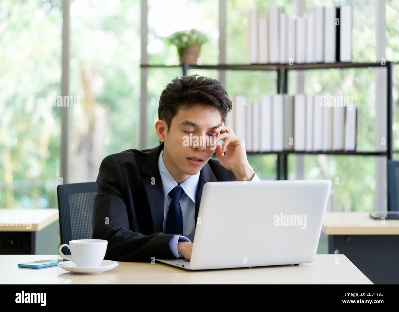 Young asian employee take a nap in the office while working on laptop ...