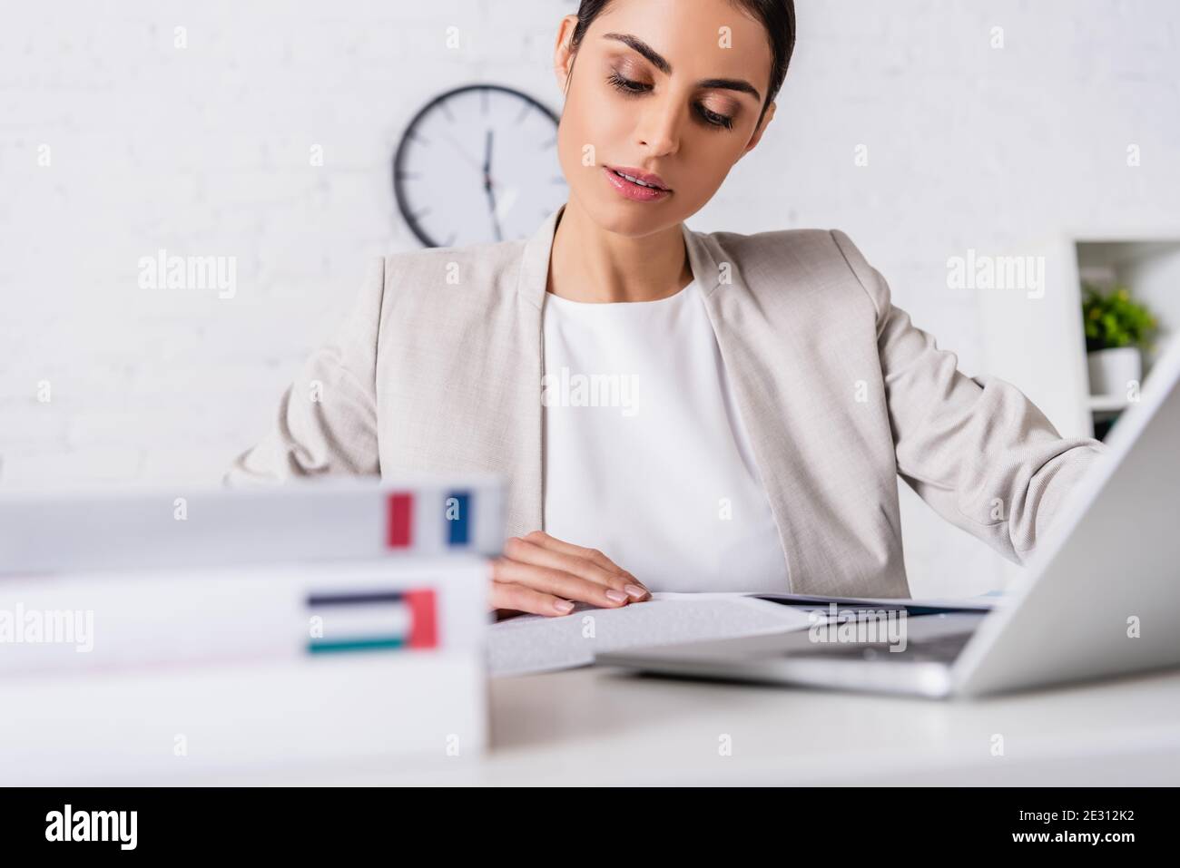 focused translator working near laptop and dictionaries of french and ...