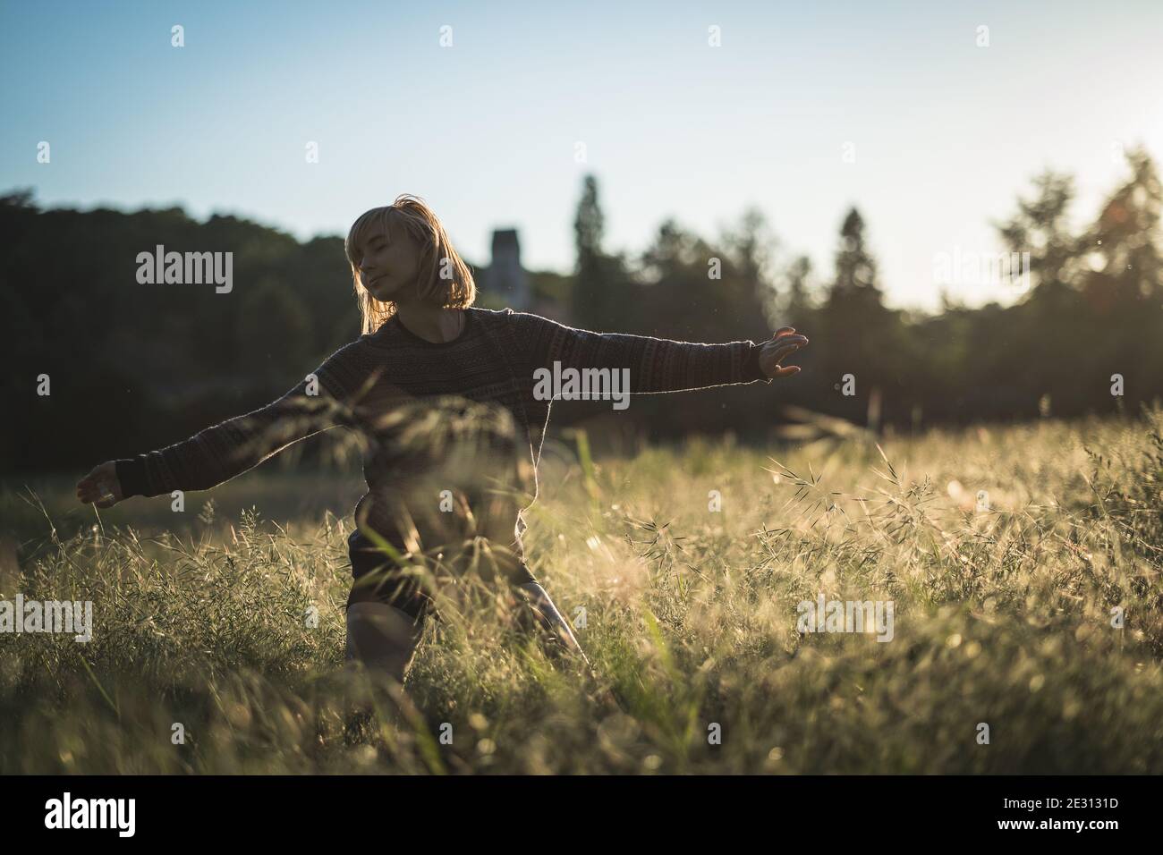 A young woman dancing in tall grass during golden hour Stock Photo - Alamy