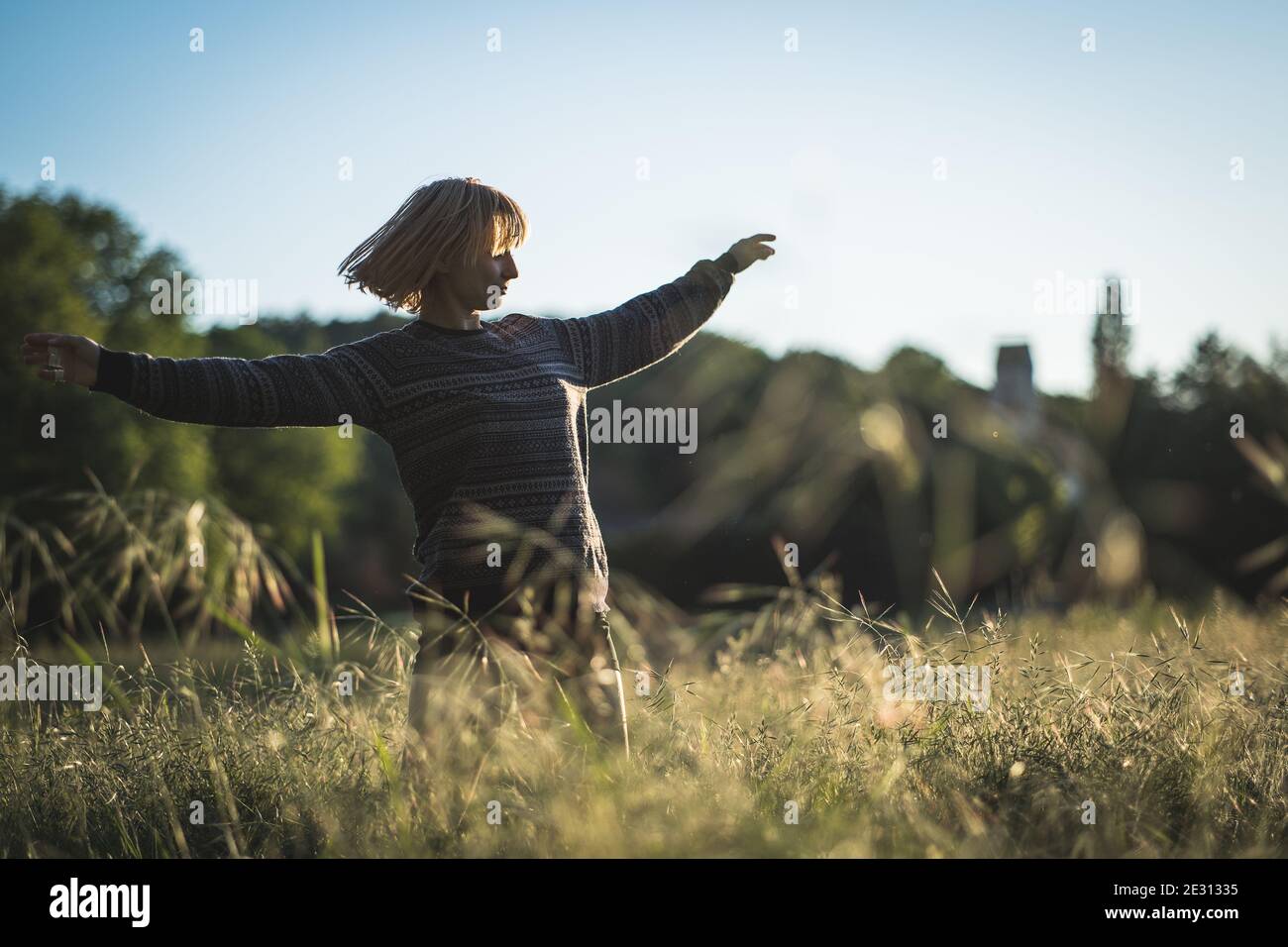 A young woman dancing in tall grass during golden hour Stock Photo - Alamy