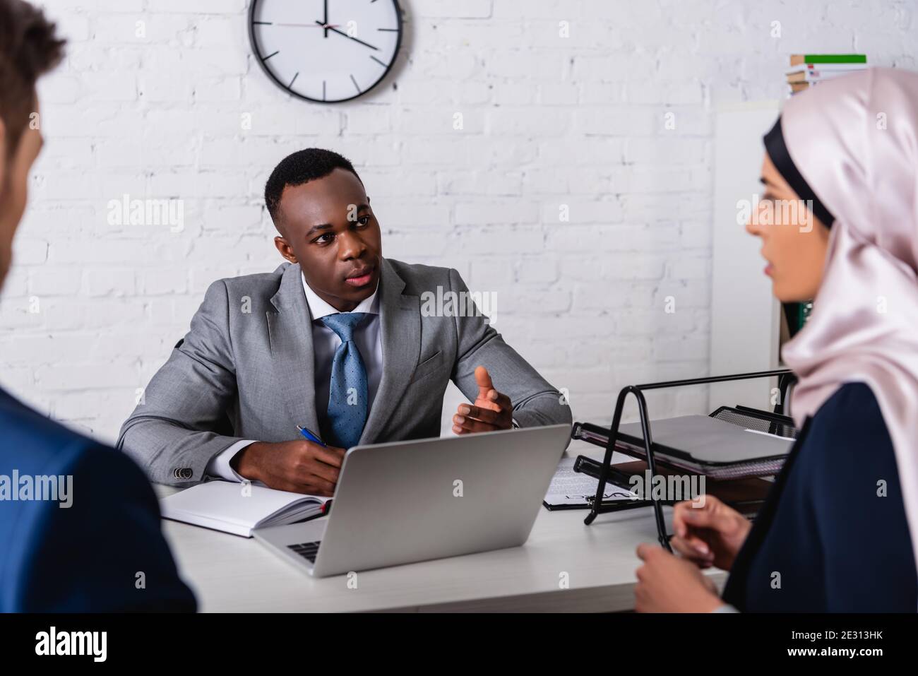 african american businessman gesturing while talking to arabian ...