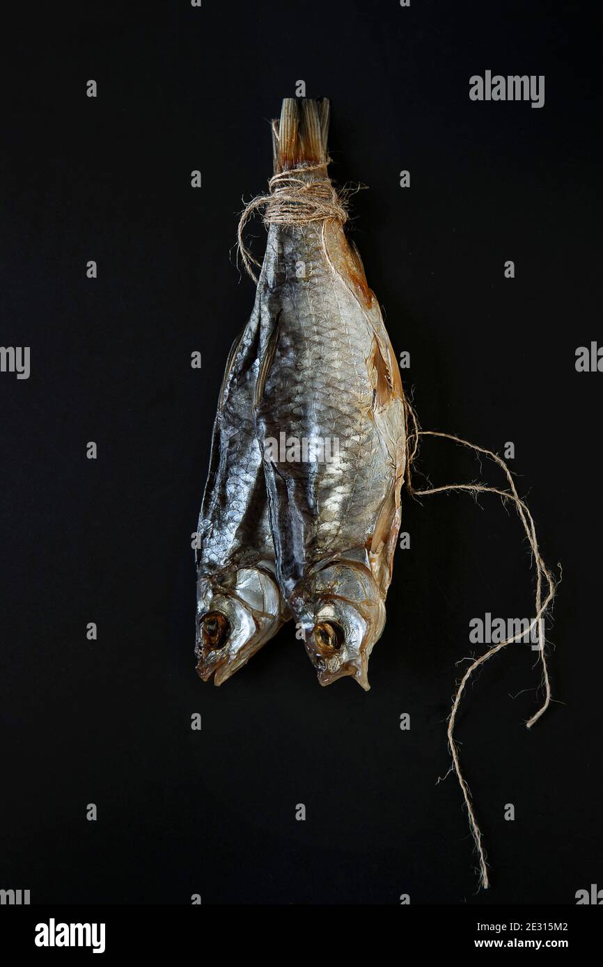 Close up top view shot of two dried salted fish lying on a black ...