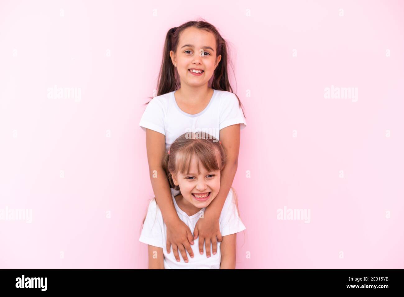 Two little girls - best friends, isolated over on a pink background ...