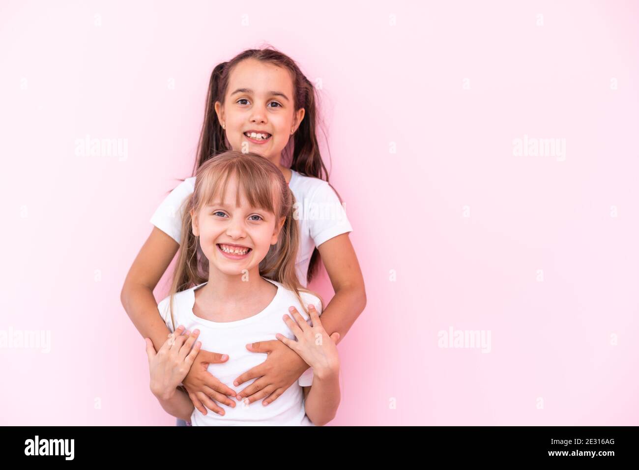 Two little girls - best friends, isolated over on a pink background ...