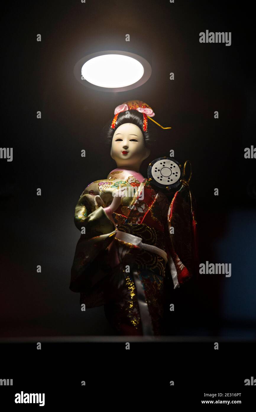 Traditional Japanese Geisha figure with overhead light and dark ...
