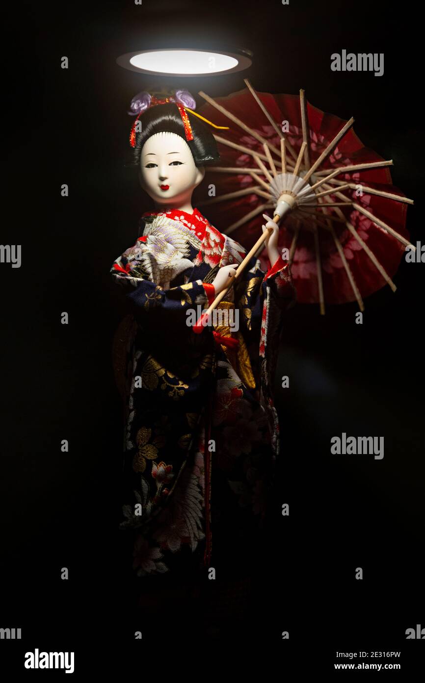 Traditional Japanese Geisha figure with overhead light and dark ...