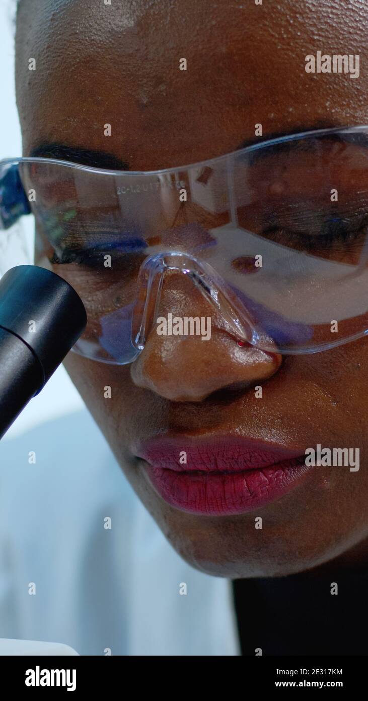 Close up of african woman doctor analysing virus using microscope ...