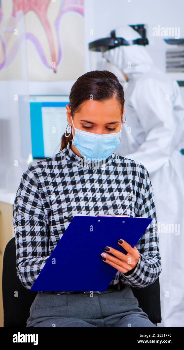 Patient with face protection mask writing on registration form in ...
