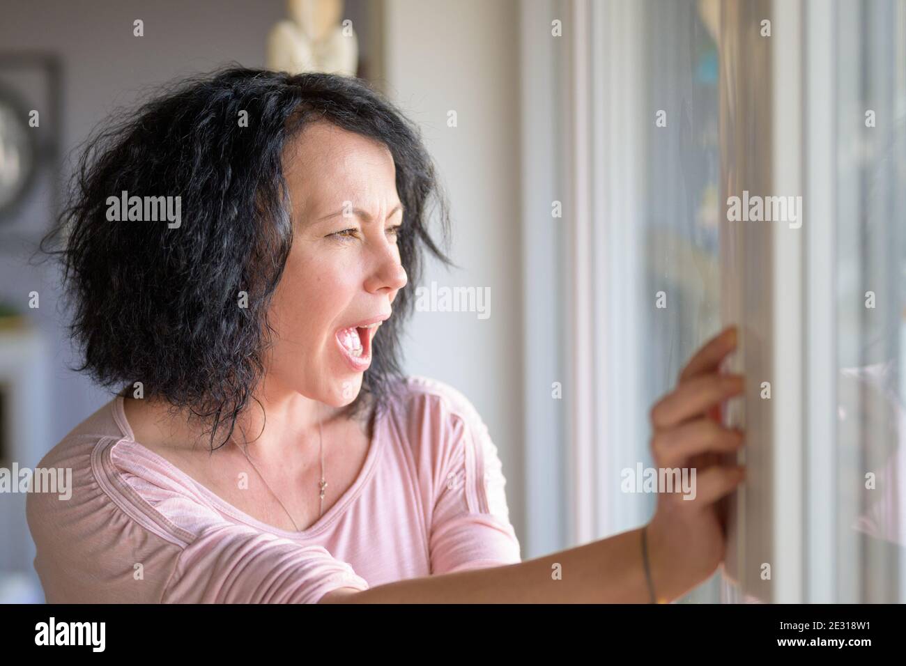 Crying woman indoors during the Covid-19 pandemic lockdown standing ...