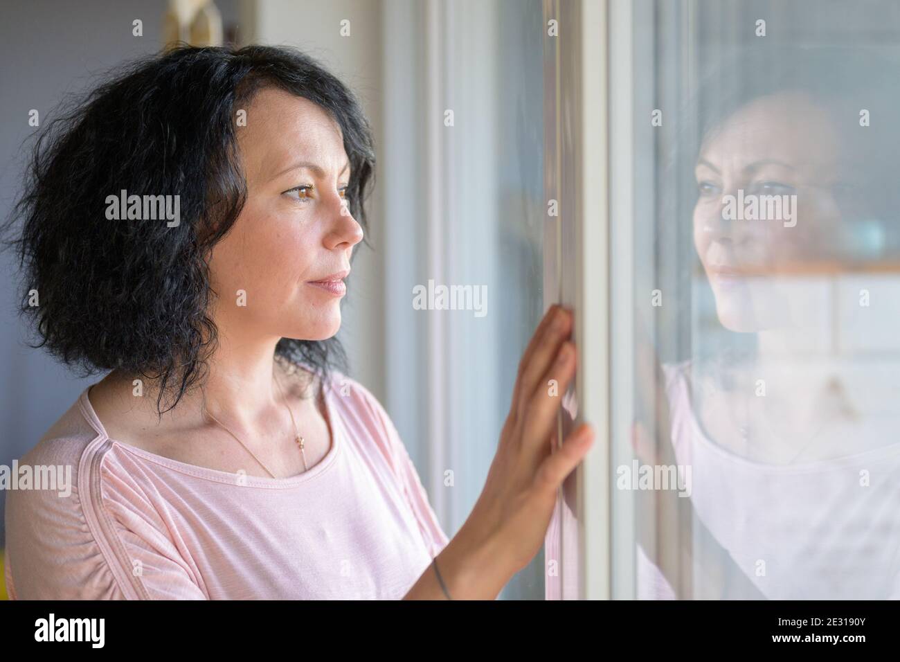 Woman indoors during the Covid-19 pandemic lockdown standing leaning a ...