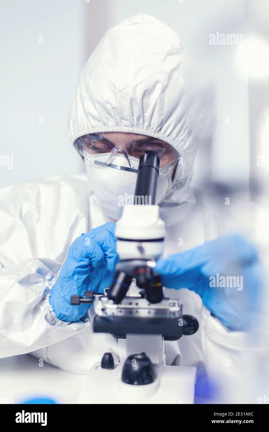 Medical engineer in ppe suit in modern laboratory looking at ...