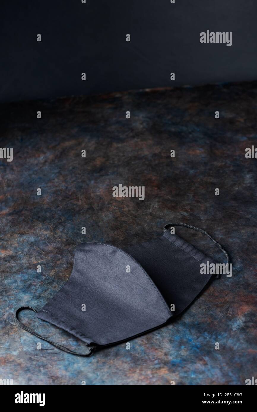 Handmade black protective mask on a dark background. Antivirus reusable ...