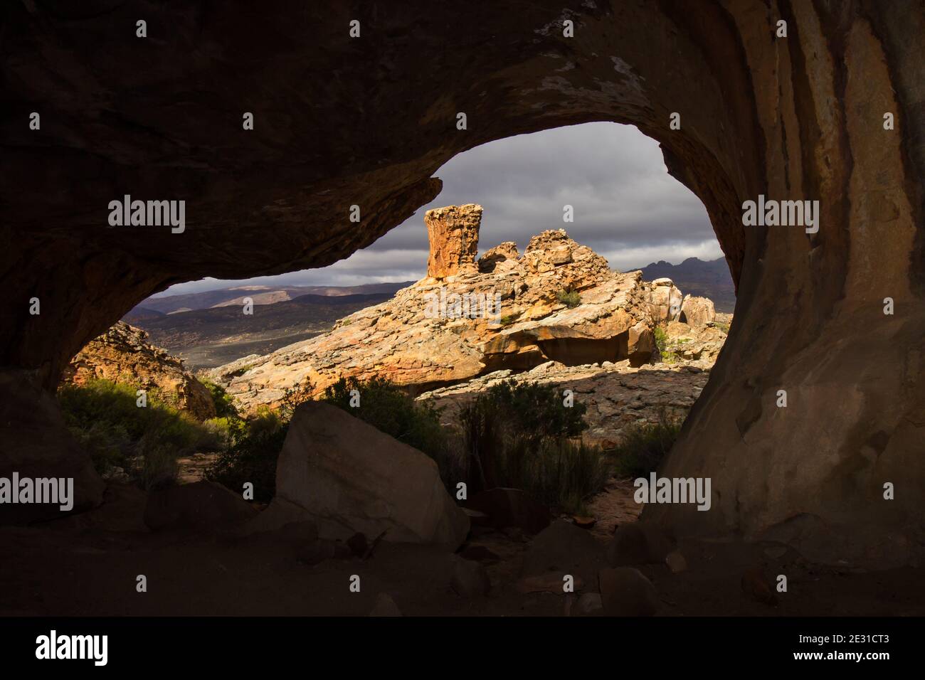 An eroded sandstone pillar framed by the entrance of a small cave in ...
