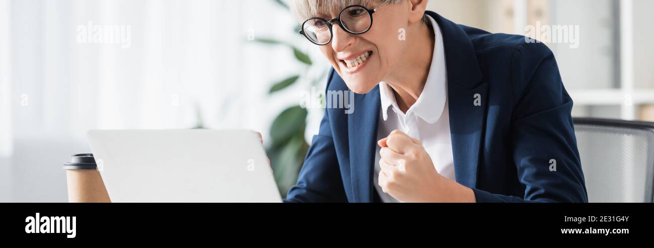 worried team leader in glasses cheering while looking at laptop, banner ...