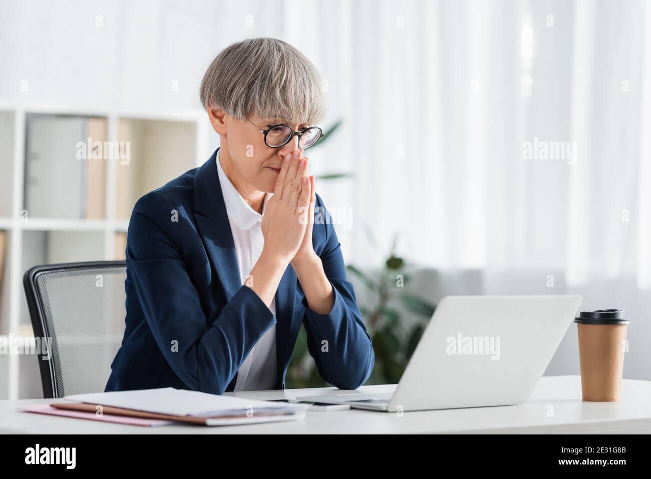 worried team leader in glasses with praying hands looking at laptop on ...