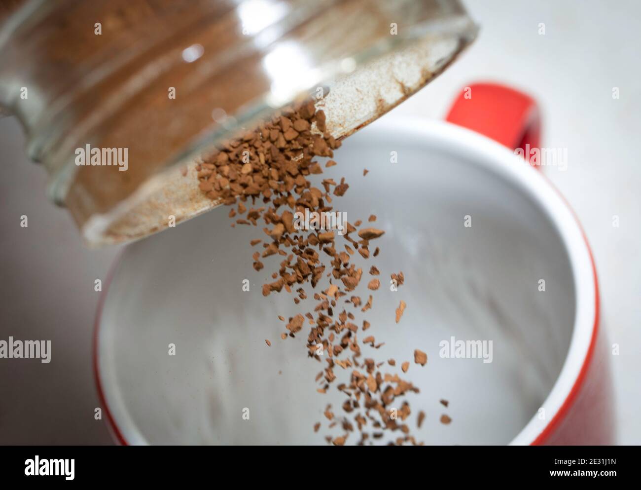 Preparing instant coffee, sprinkling grains granules poured into a cup ...