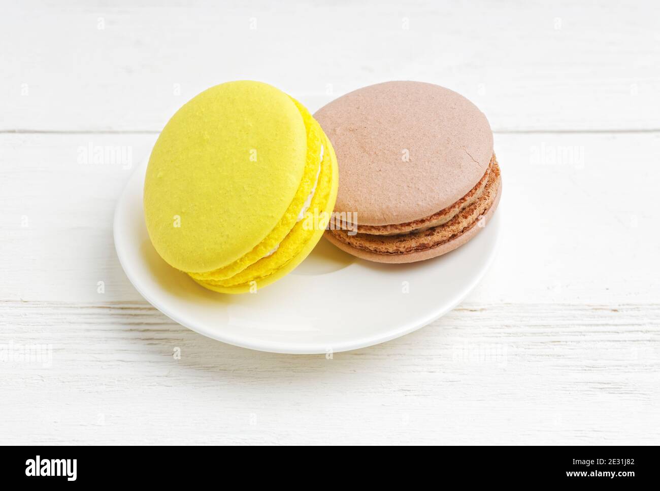 Close-up two macaroons lemon and chocolate on white plate on white ...