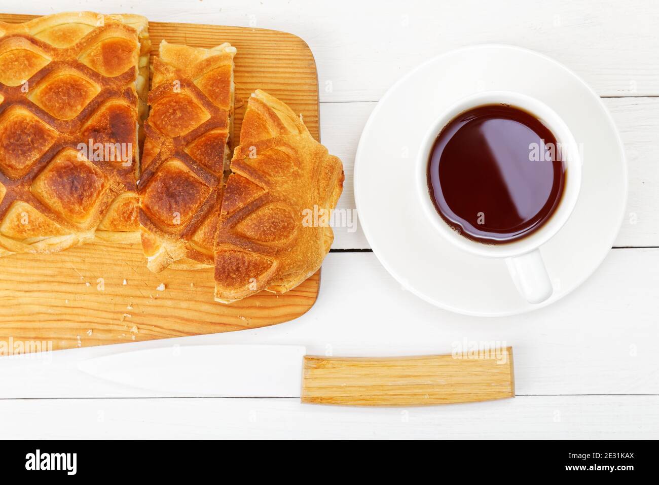 Closeup strudel with apples and cinnamon, cup of tea and knife on white ...