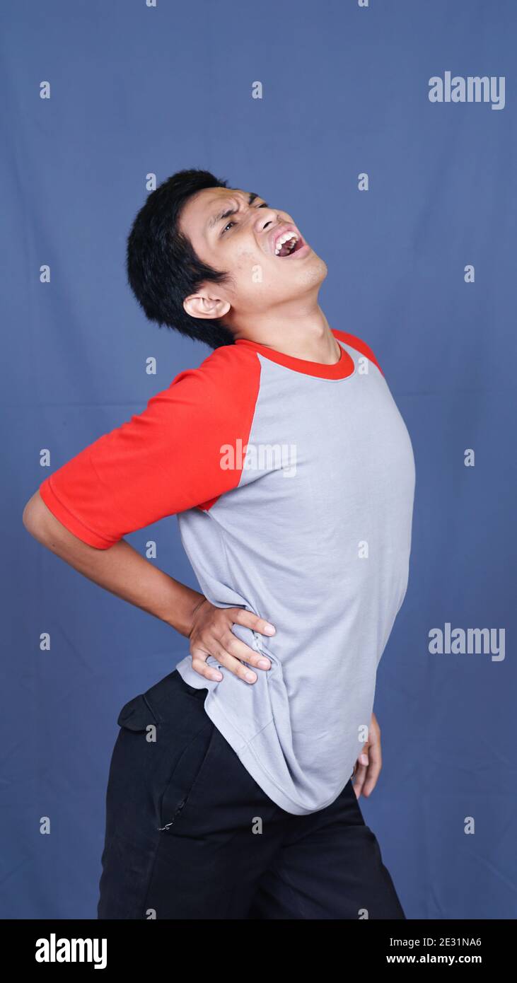 Asian man back pain isolated blue background Stock Photo - Alamy