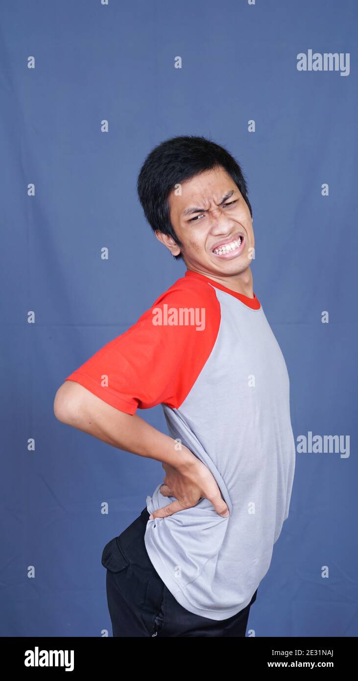 Asian man back pain isolated blue background Stock Photo - Alamy