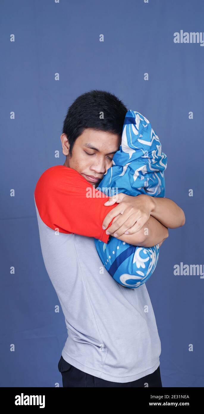 asian man sleepy and hug pillow isolated with blue background Stock ...
