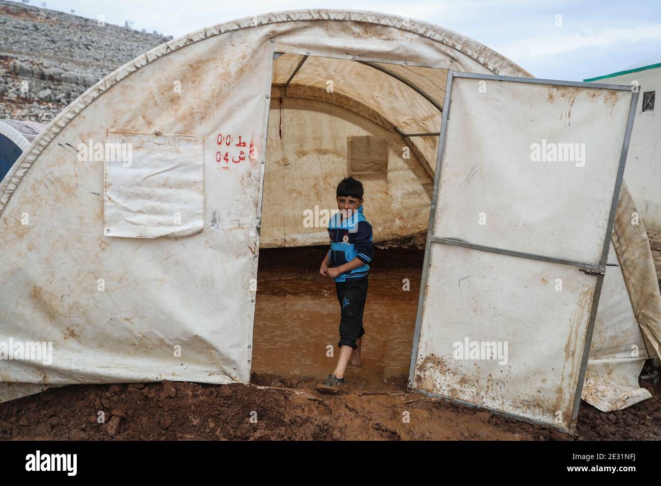 Sarmada, Syria. 16th Jan, 2021. A Syrian boy stands at the entrance of ...