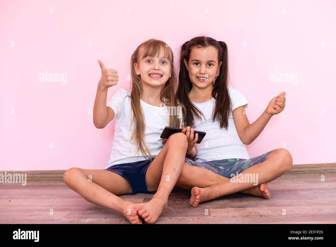 Two little girls - best friends, isolated over on a pink background ...