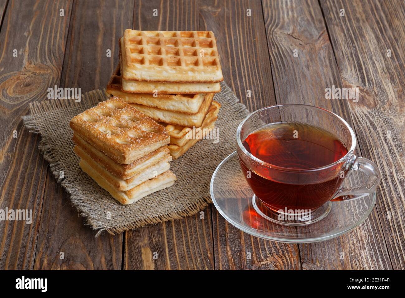Cup of tea and stack of waffles and cookies on wooden table Stock Photo ...