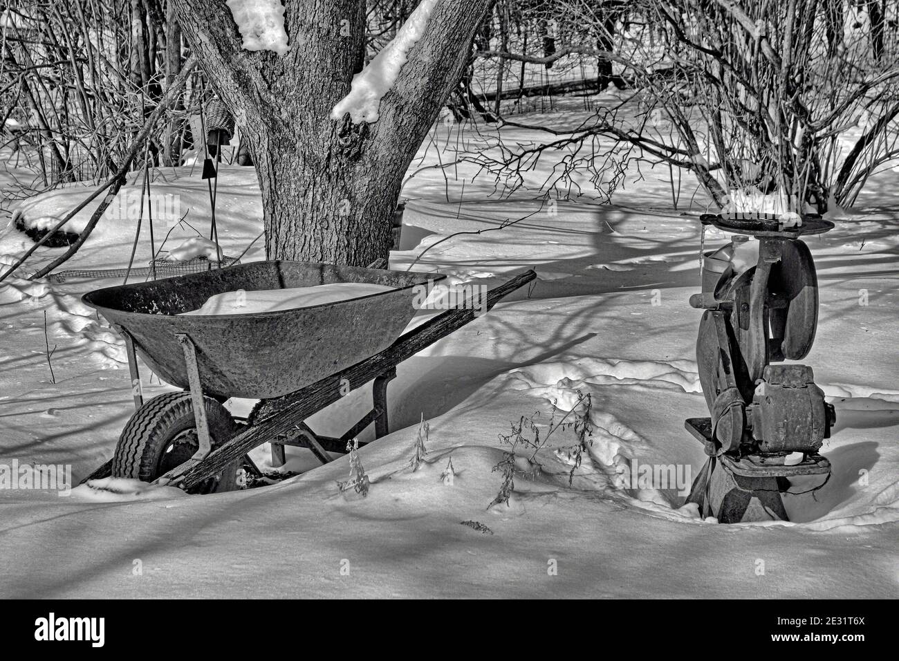 Grayscale shot of a garden wheelbarrow filled with snow and stone ...