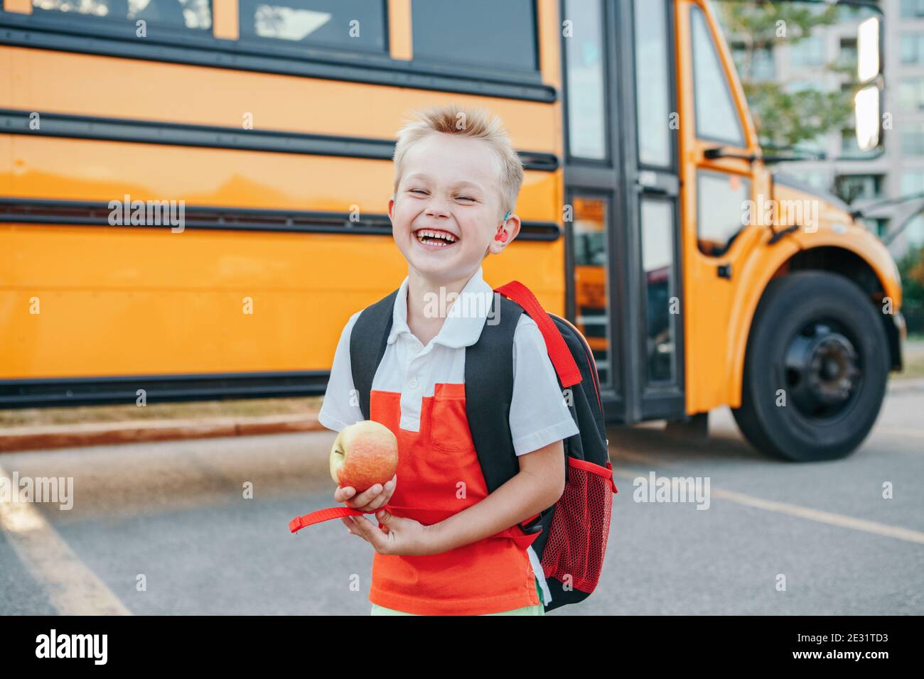 Happy laughing smiling Caucasian boy student by yellow bus on first ...