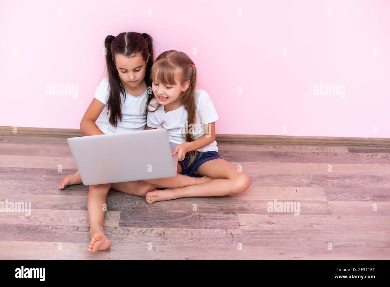 Amazed little kids girls showing white t-shirt, isolated on pink ...