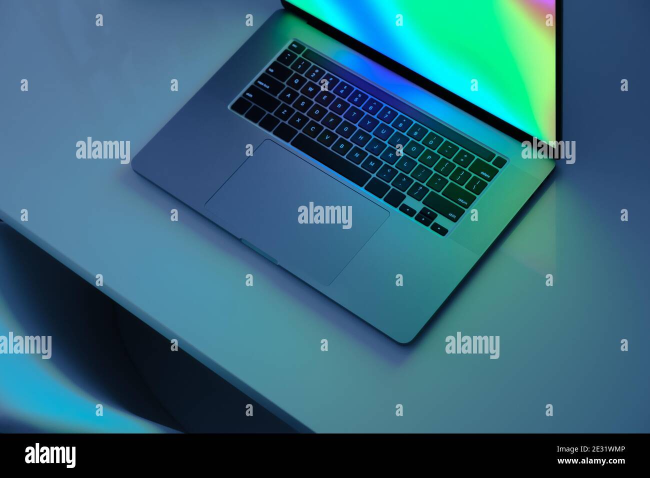 Laptop computer with a vibrant screen standing on a table, low key blue ...