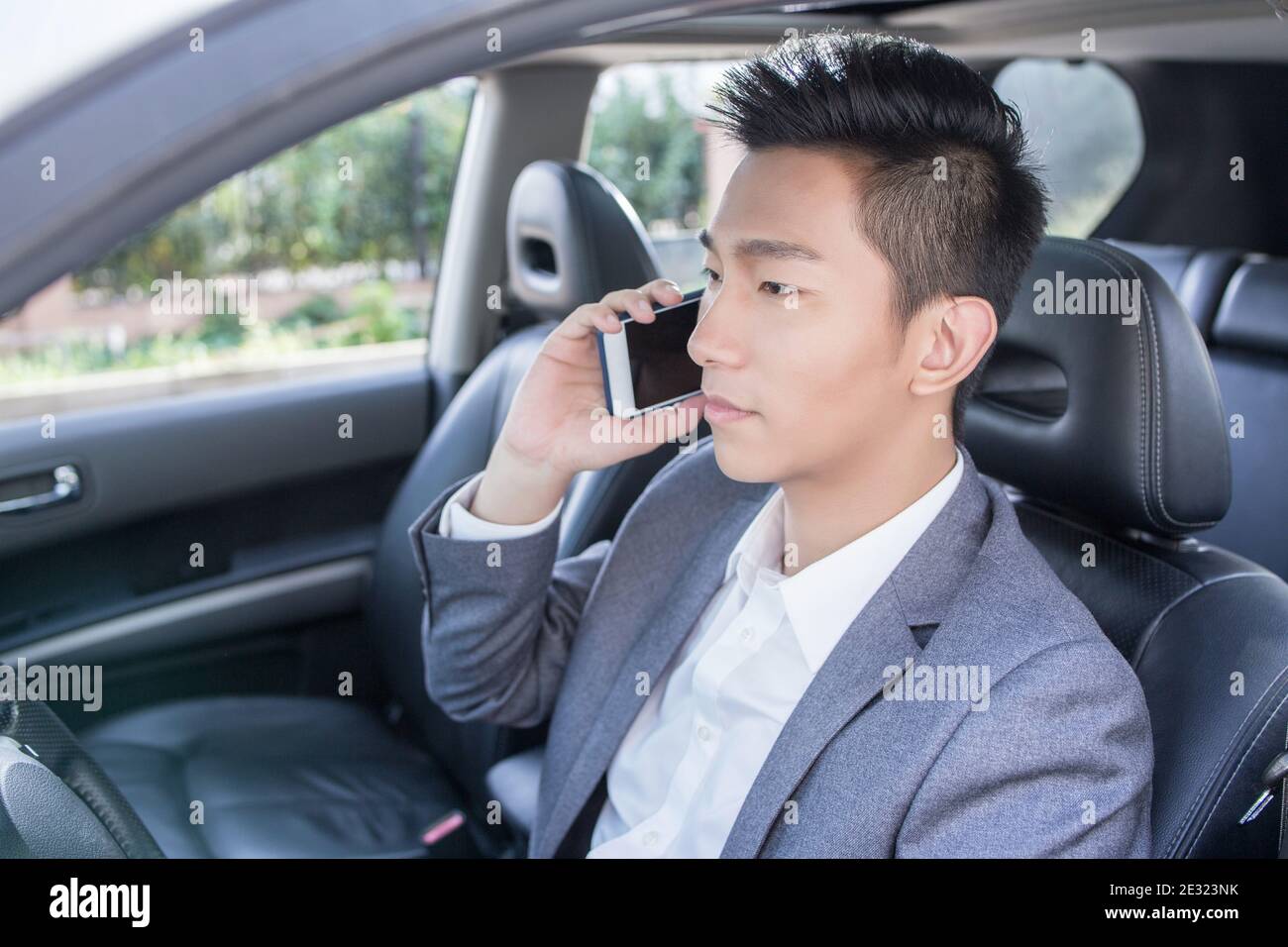 Asian man driving car using phone Stock Photo - Alamy