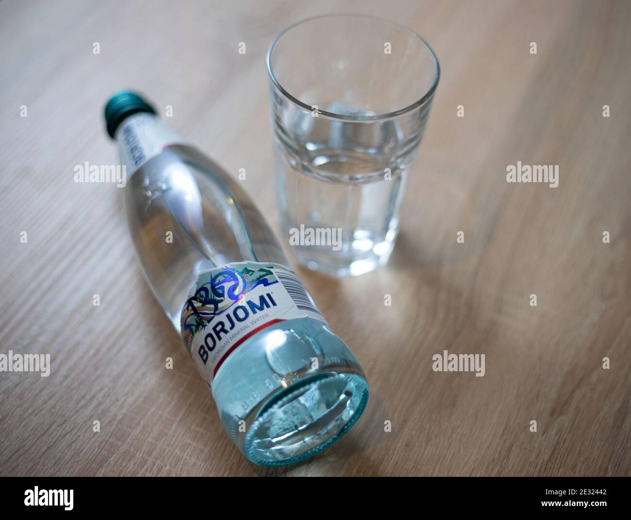 Glass bottle of Borjomi sparkling Georgian mineral water on wooden table. Borjomi is the most ...