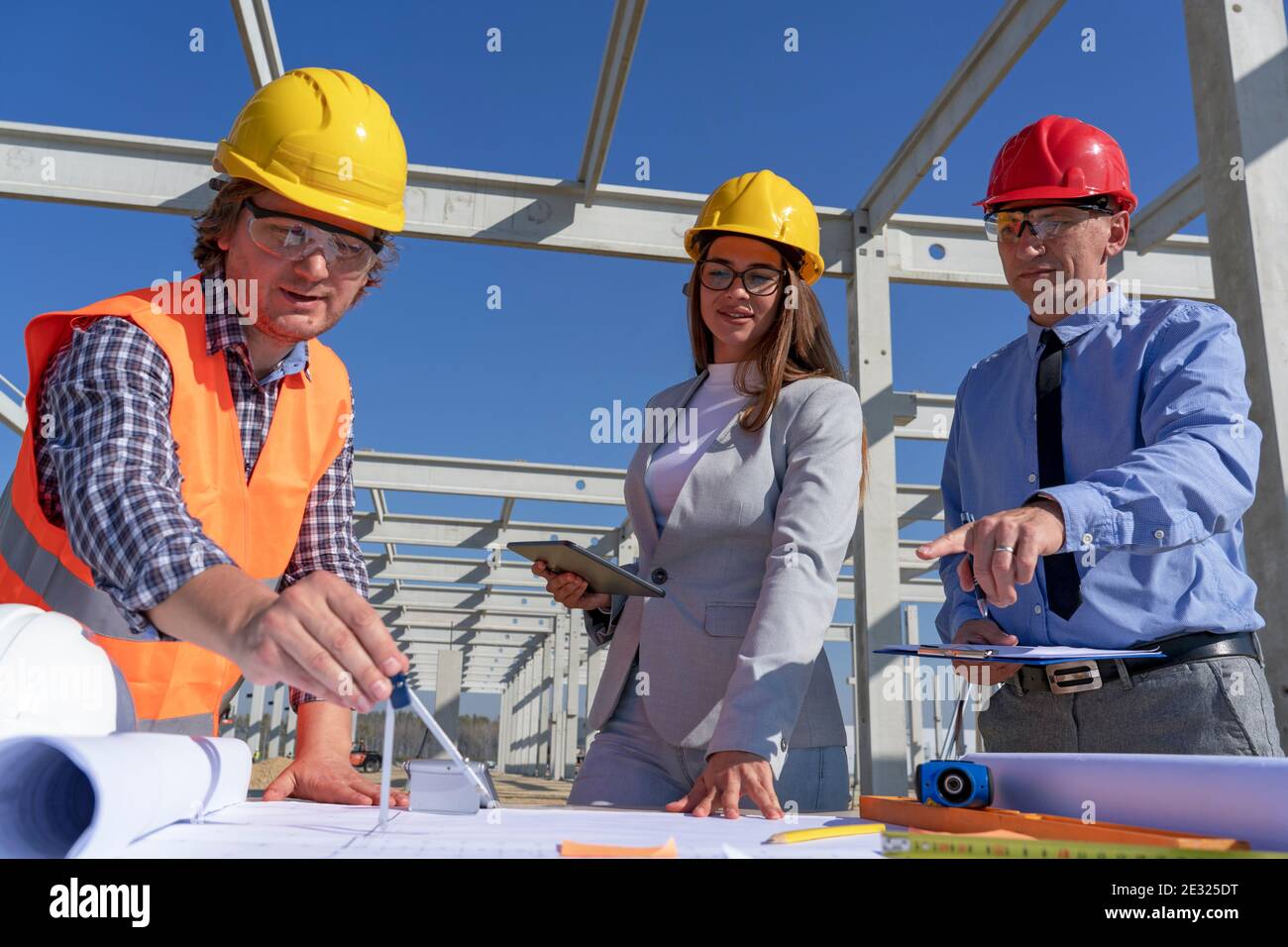 Construction Project Team in Hardhats Working on a Blueprint. Business ...