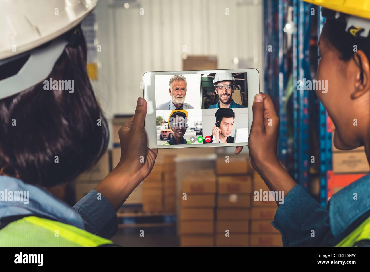 Warehouse staff talking on video call at computer screen in storage ...