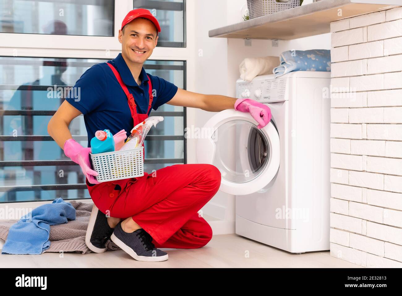 Plumber in overalls with tools is repairing a washing machine in the ...