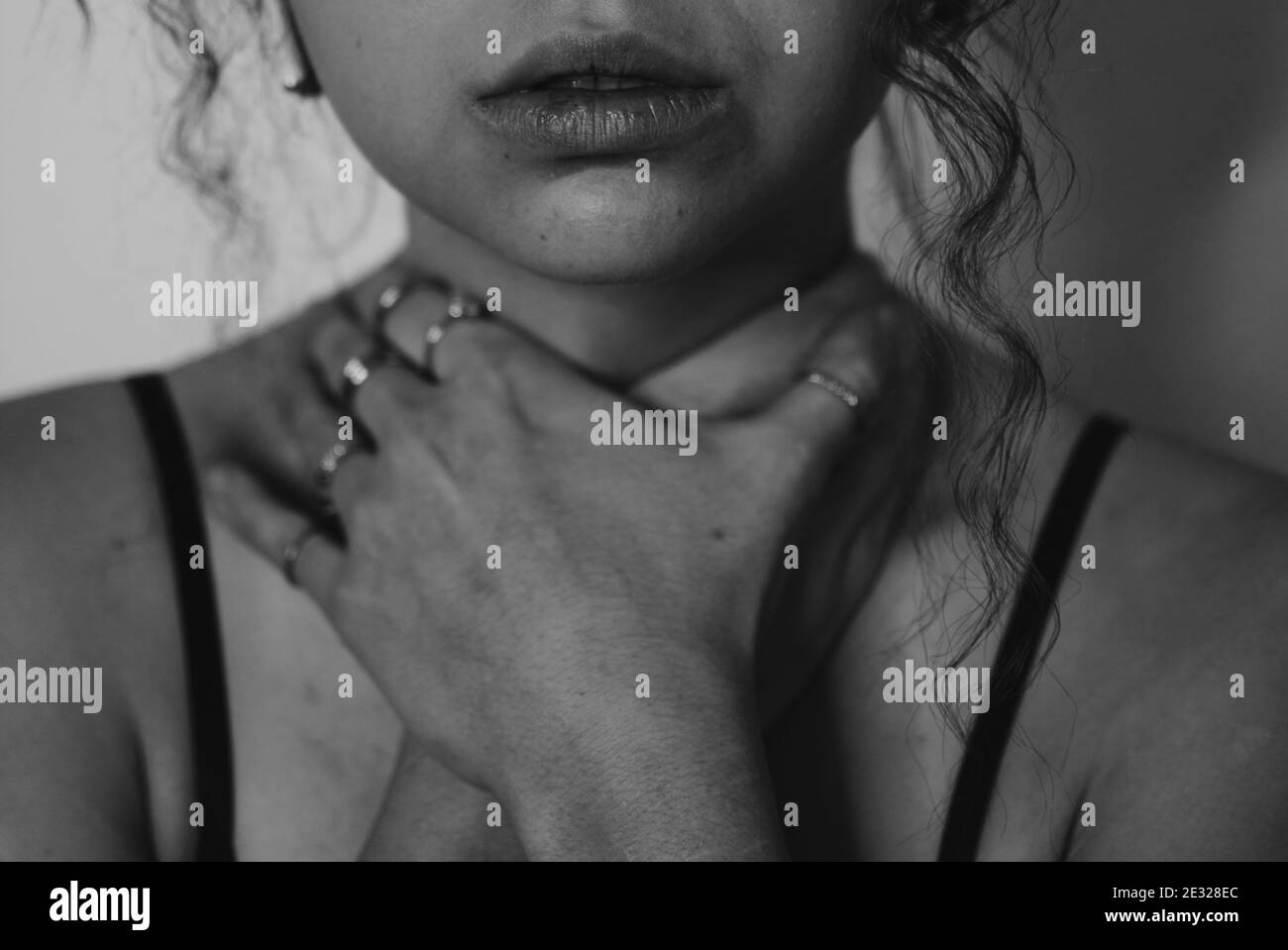 Grayscale shot of a young female with her hand on the neck, woman ...