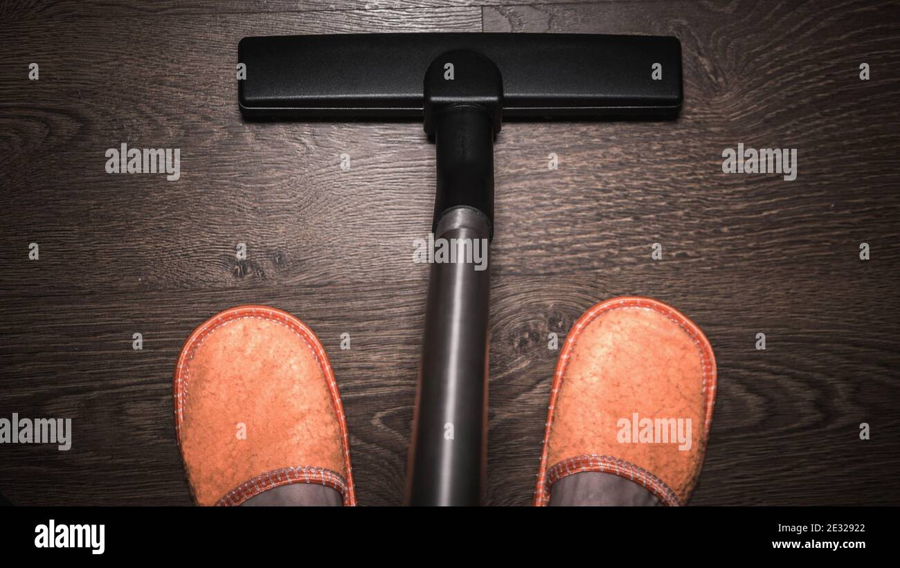 Male feet in room slippers with a vacuum cleaner, cleaning the house ...