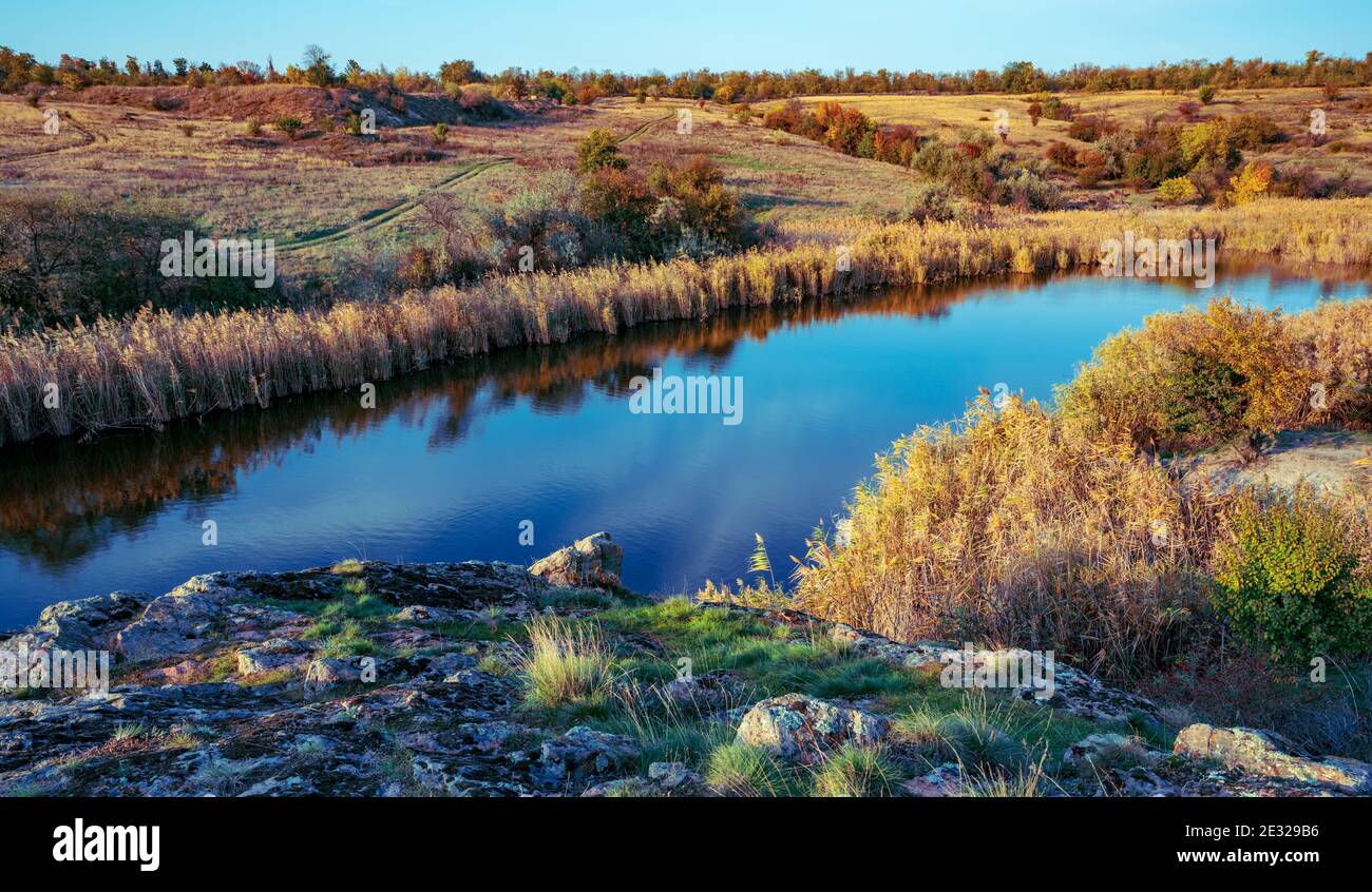 A gleaming beautiful little river among large white stones and green ...